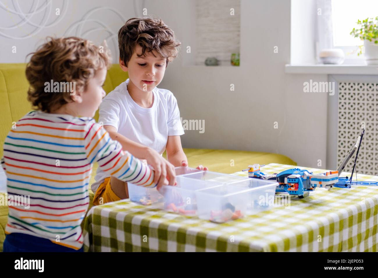 Kid collects robot from plastics details and programmed on tablet ...