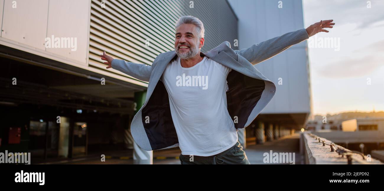 Portrait of happy energetic mature businessman with arms outstretched ...