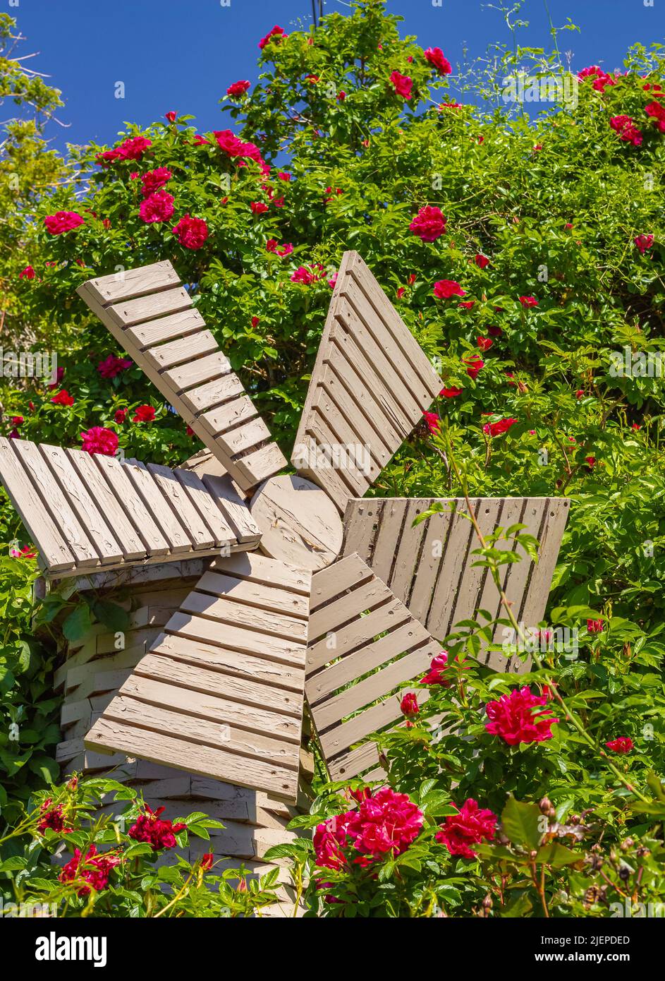 A small wooden windmill in the beautiful summer garden. Windmill and ...