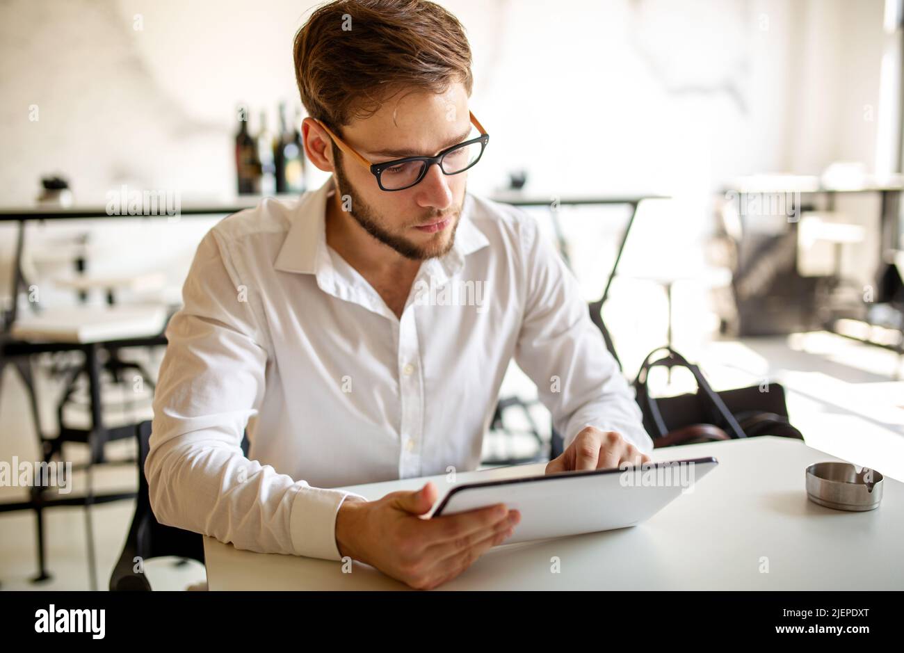 Portrait of a young business man using smart phone and working in cafe ...