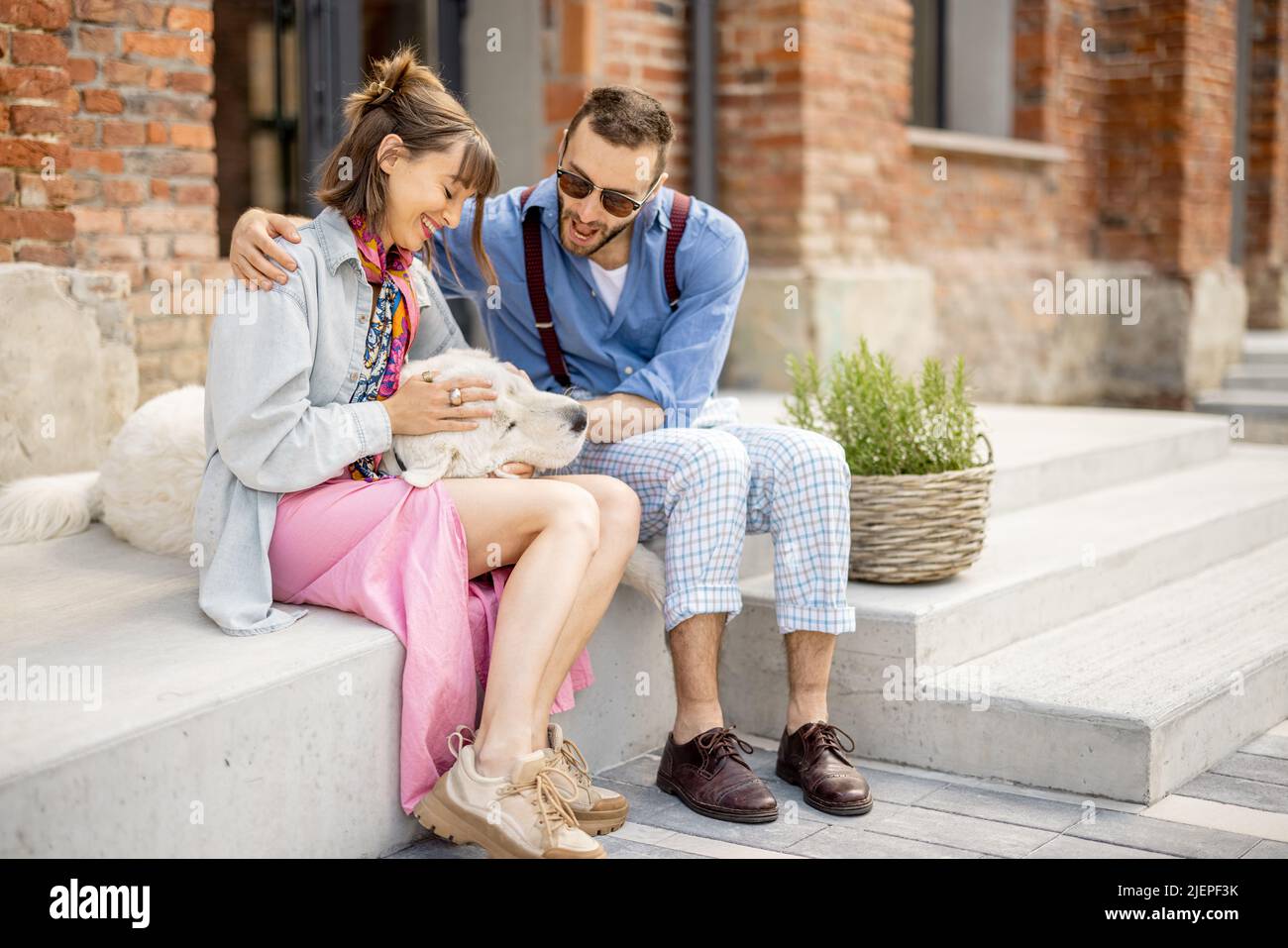 Stylish couple have fun and sit with their dog on a street Stock Photo ...