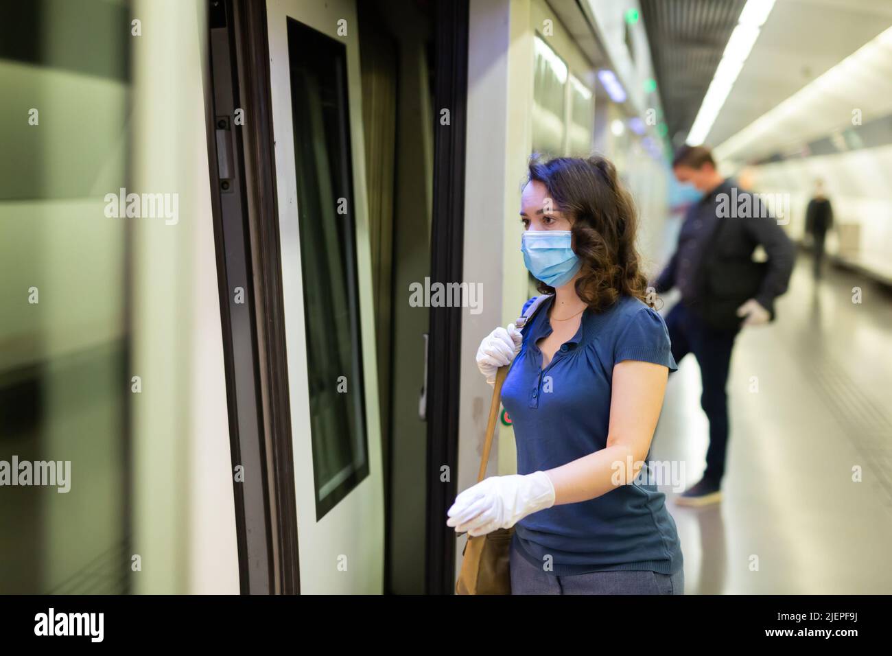 Woman in personal protective equipment is standing on platform metro ...