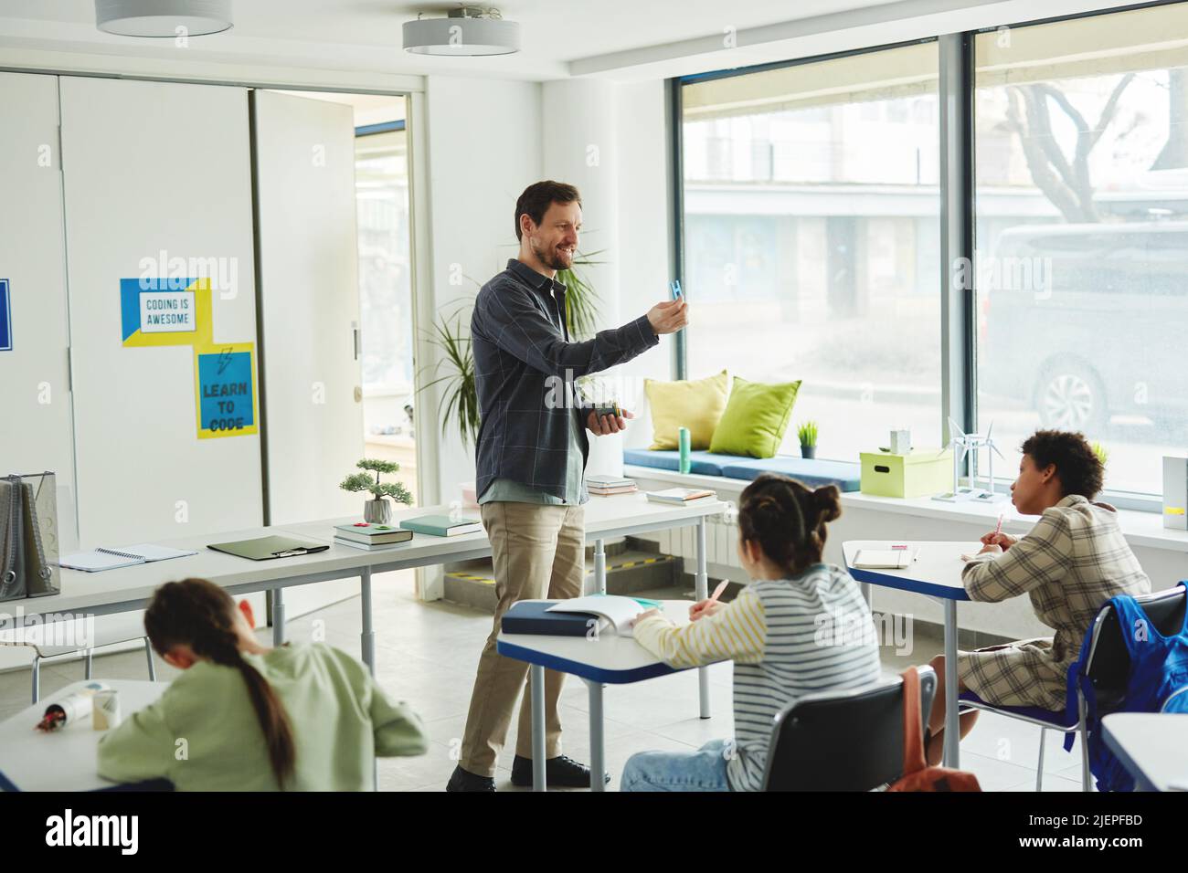 Wide angle view at smiling male teacher working with children in school ...
