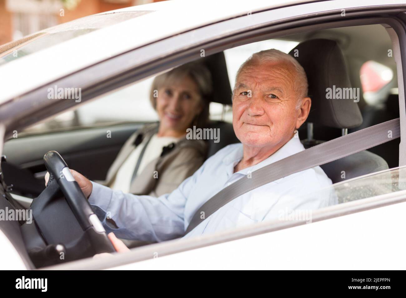 Elderly man and woman driving a car in the city. Man driving car Stock ...