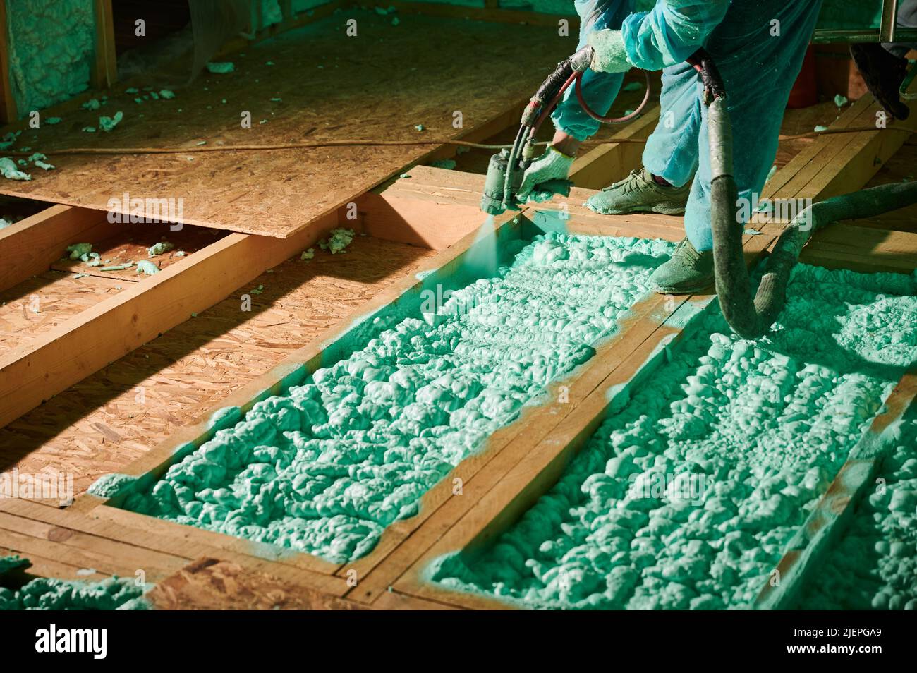 Male builder insulating wooden frame house. Cropped view of man worker ...