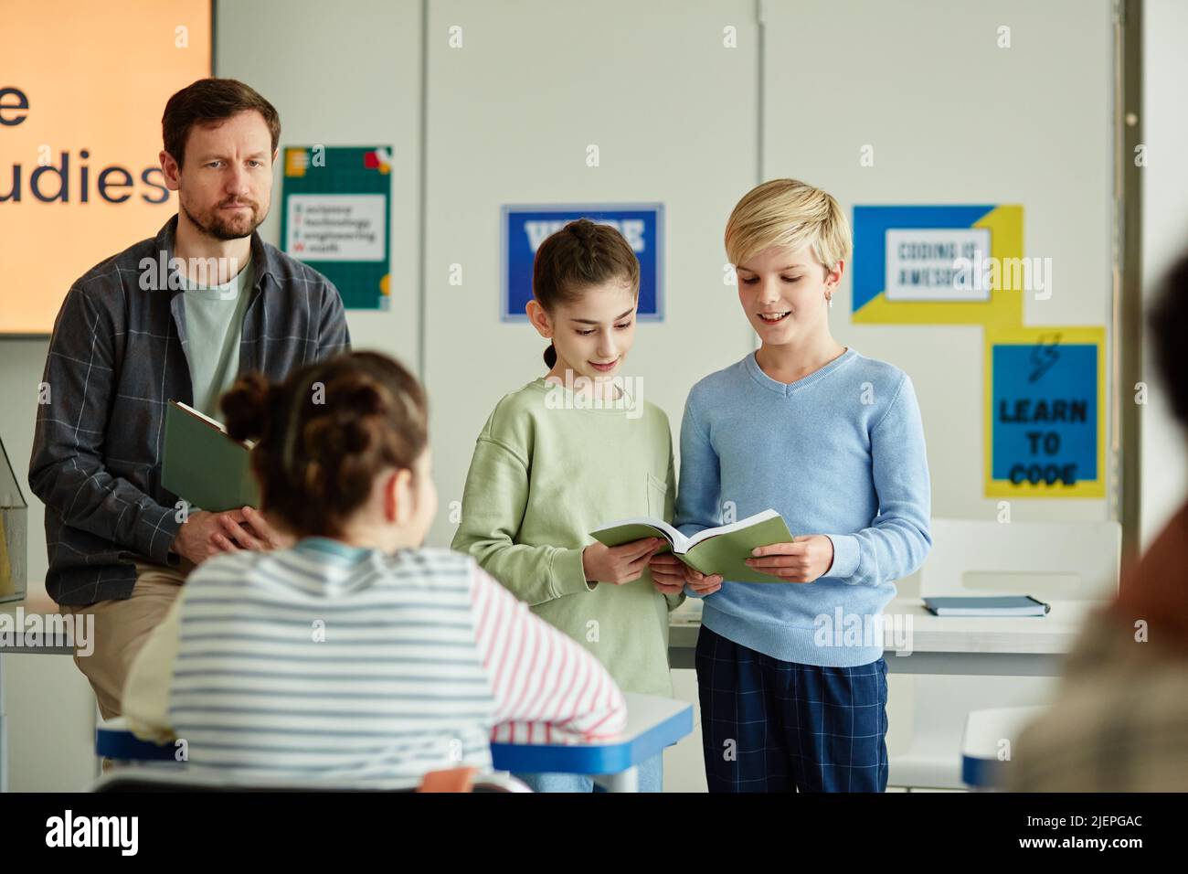 Portrait of two kids answering questions in school in front of ...