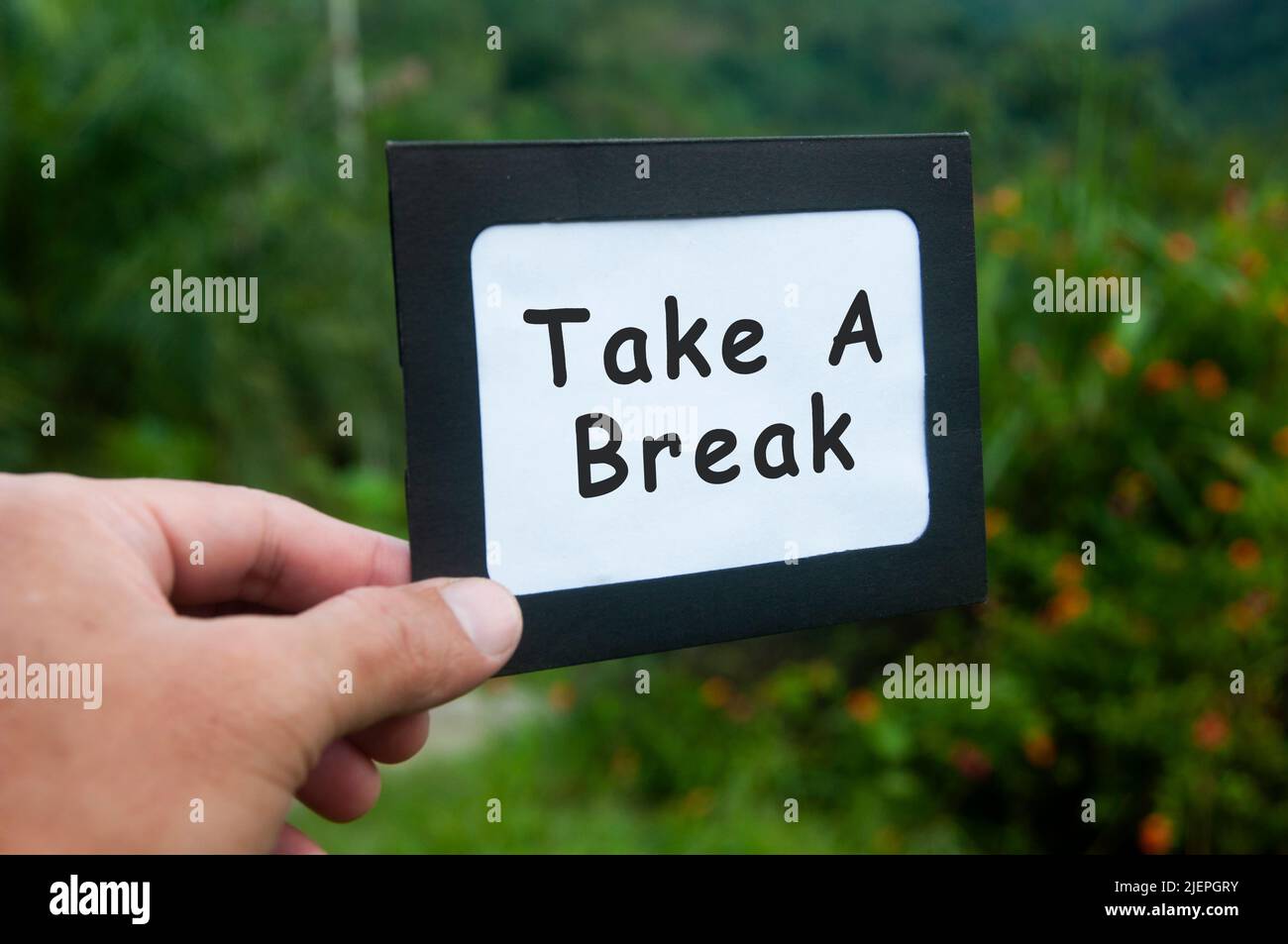 Hand holding notepad with text - Take a break. With blurred nature ...