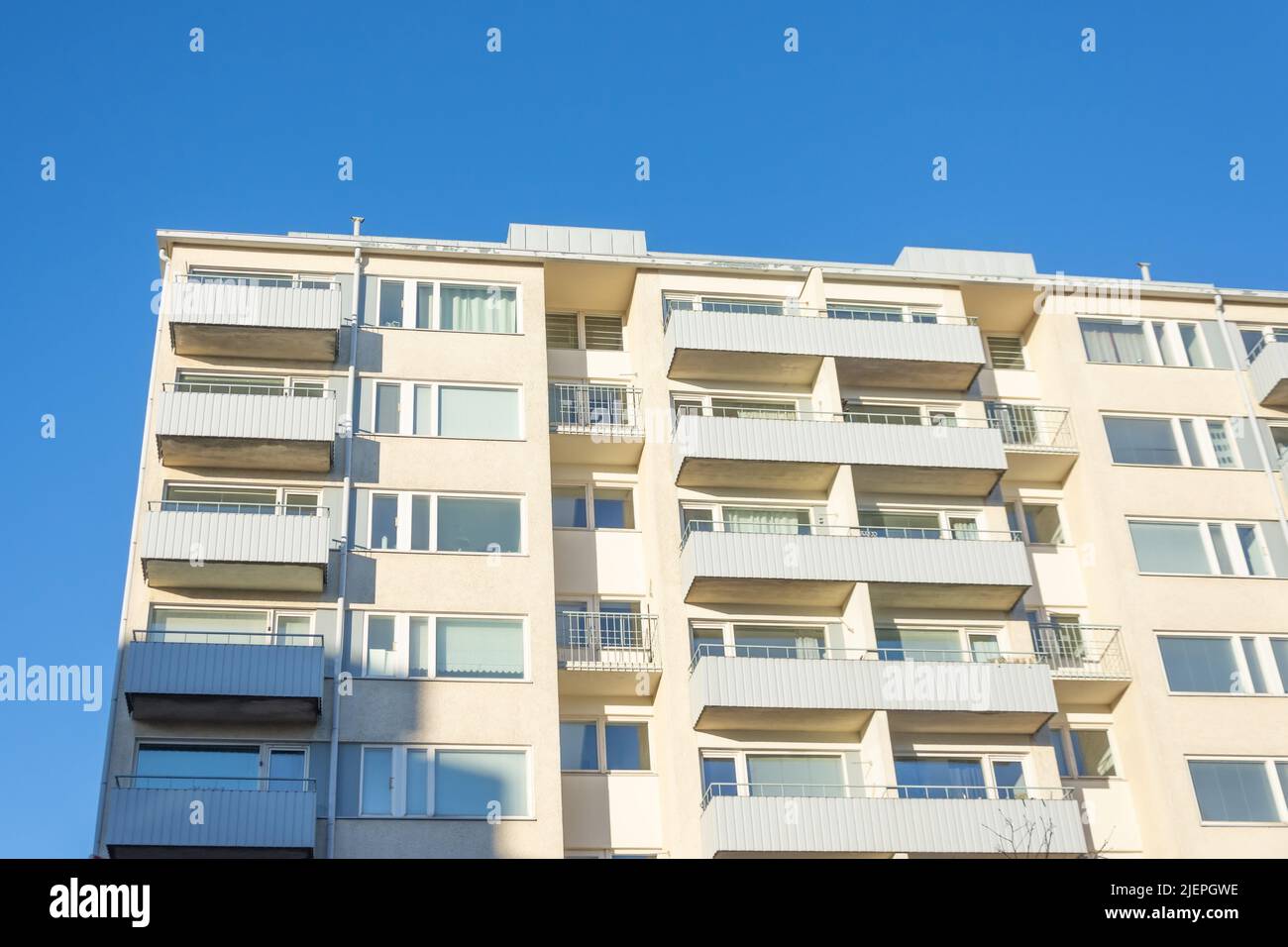 Multi-storey white concrete residential building with balconies and ...