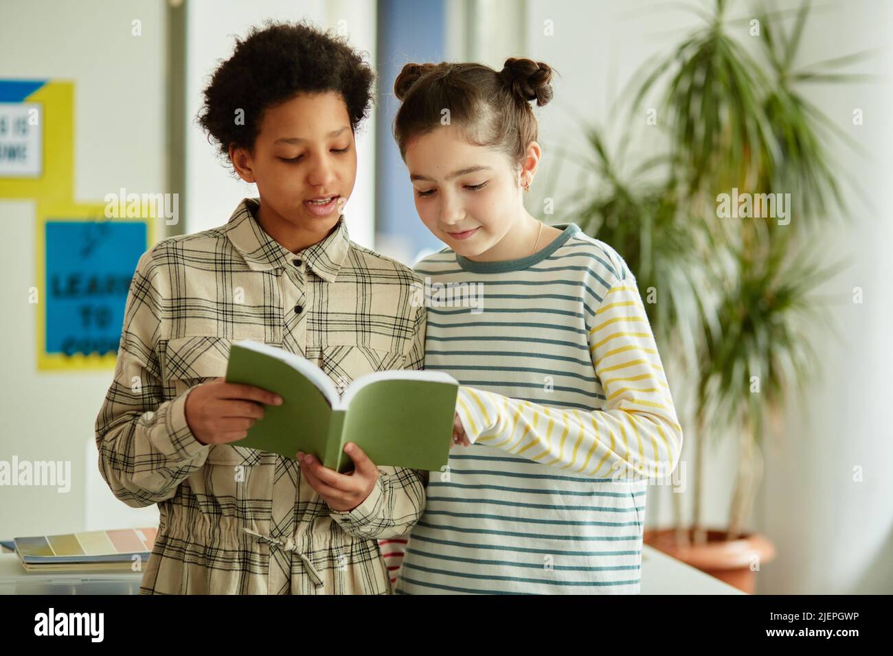 Waist up portrait of two girls answering questions in school in front ...