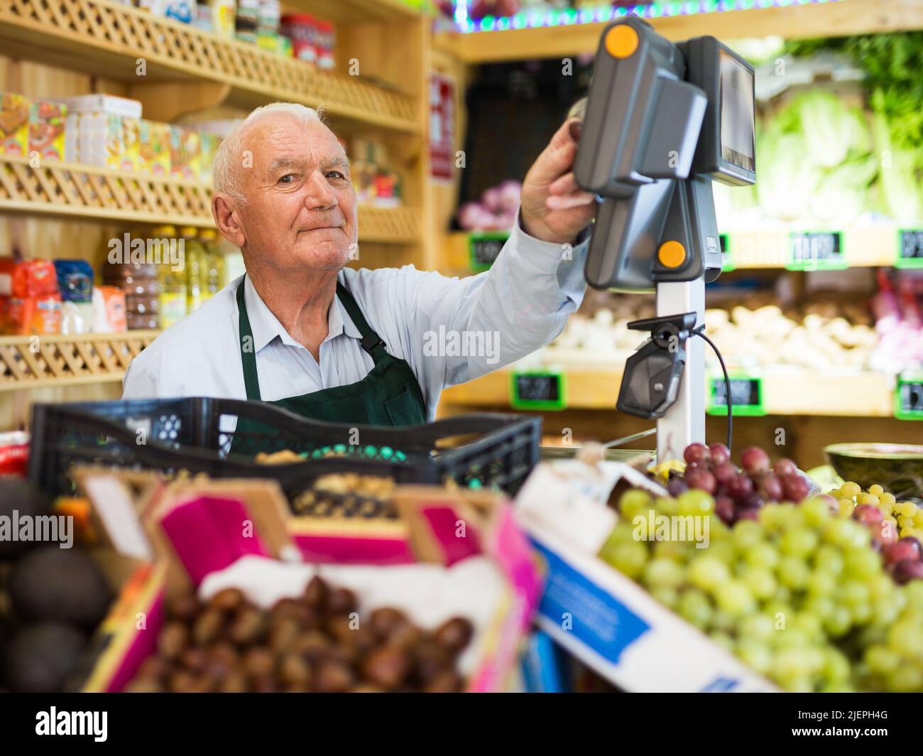 Portrait of a positive male salesperson at the checkout counter at ...