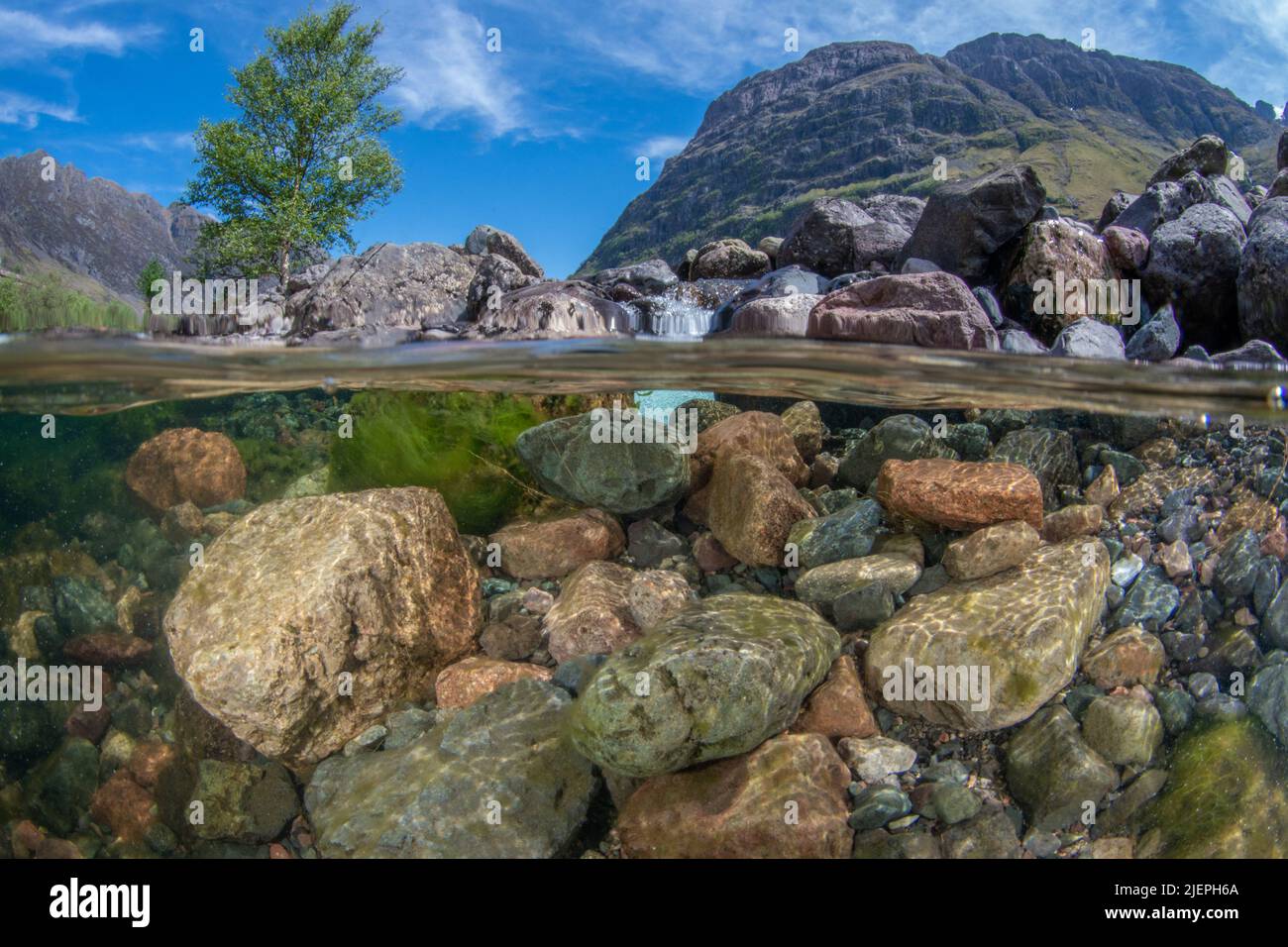 Rocks and pebbles under the River Coe on a sunny Scottish day. The ...