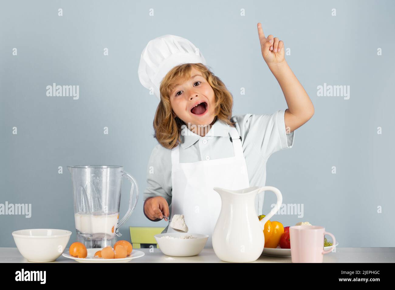 Child wearing cooker uniform and chef hat preparing food with flour on ...