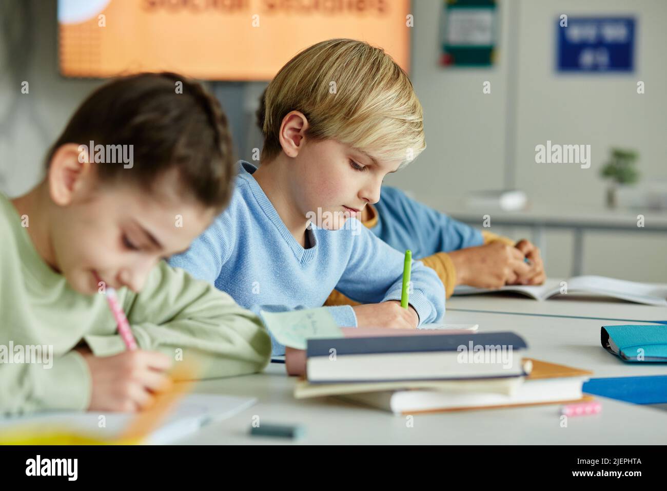 Side view portrait of young blonde boy taking test in school classroom ...