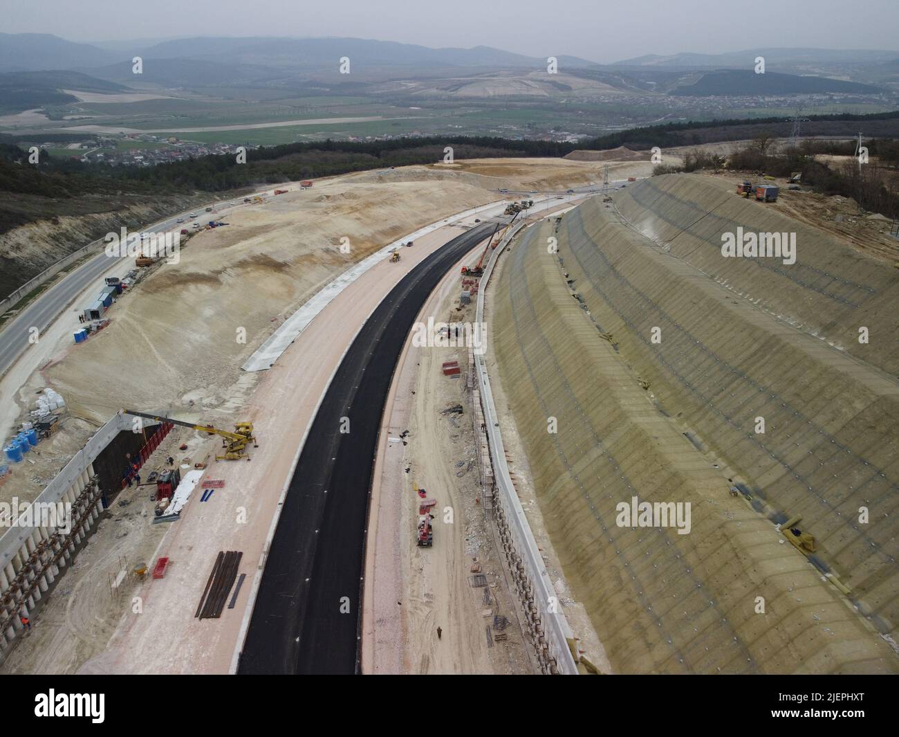 Workers reinforce the slope over the new road. Road construction in ...