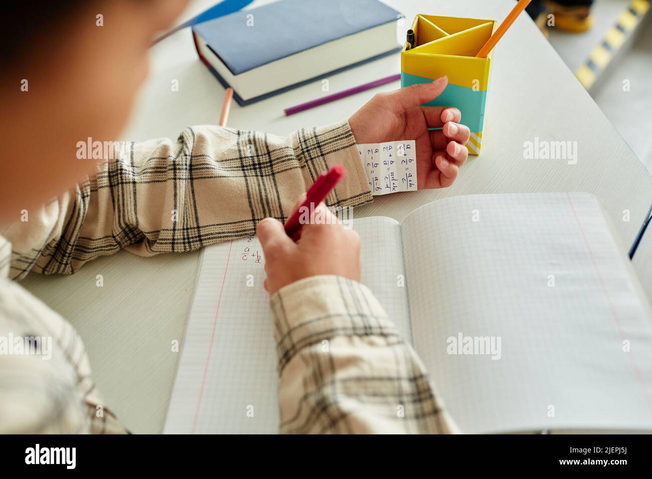 Close up of unrecognizable young boy cheating during test in school and ...