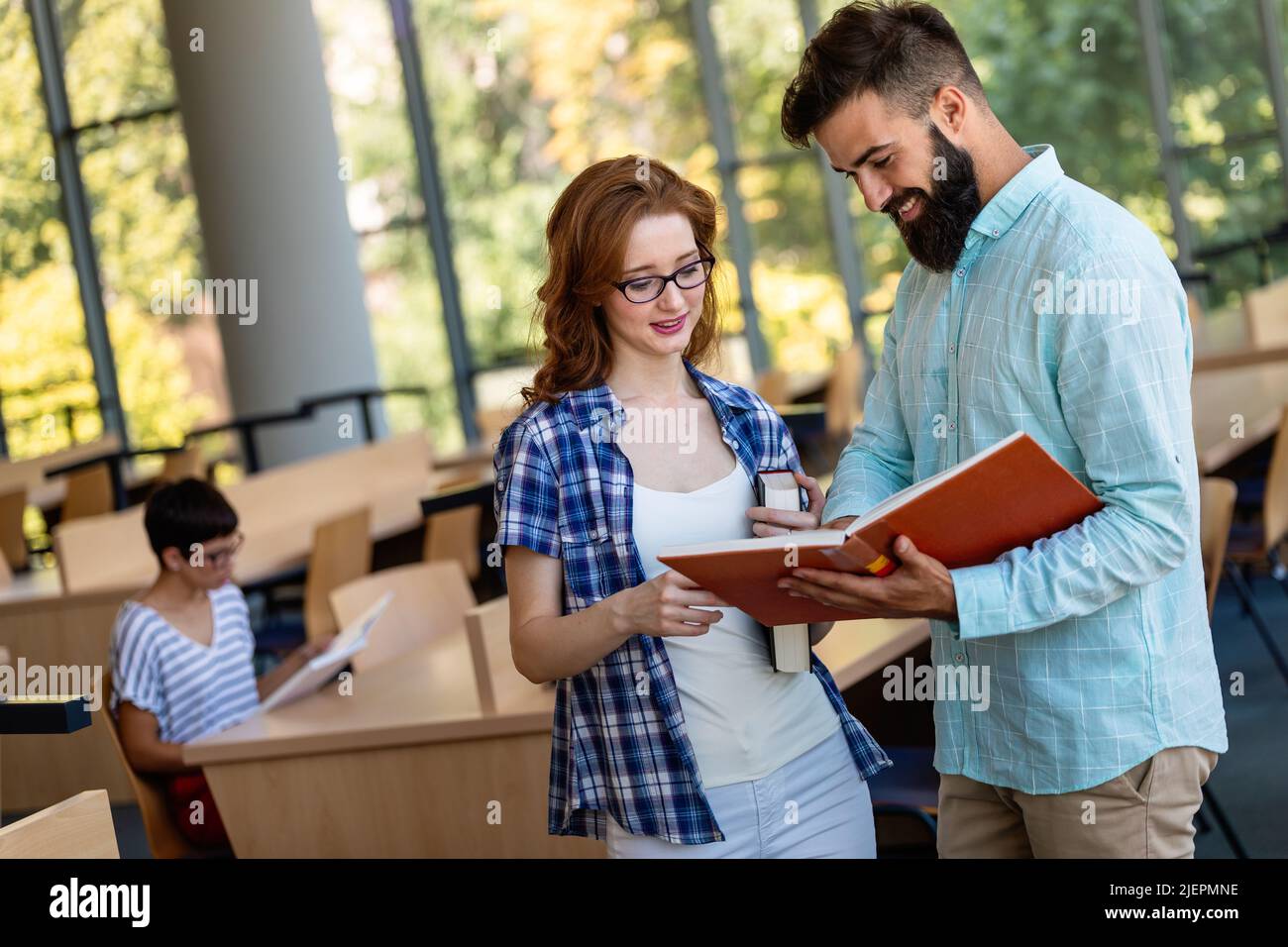 Happy university students studying with books in library. Group of ...