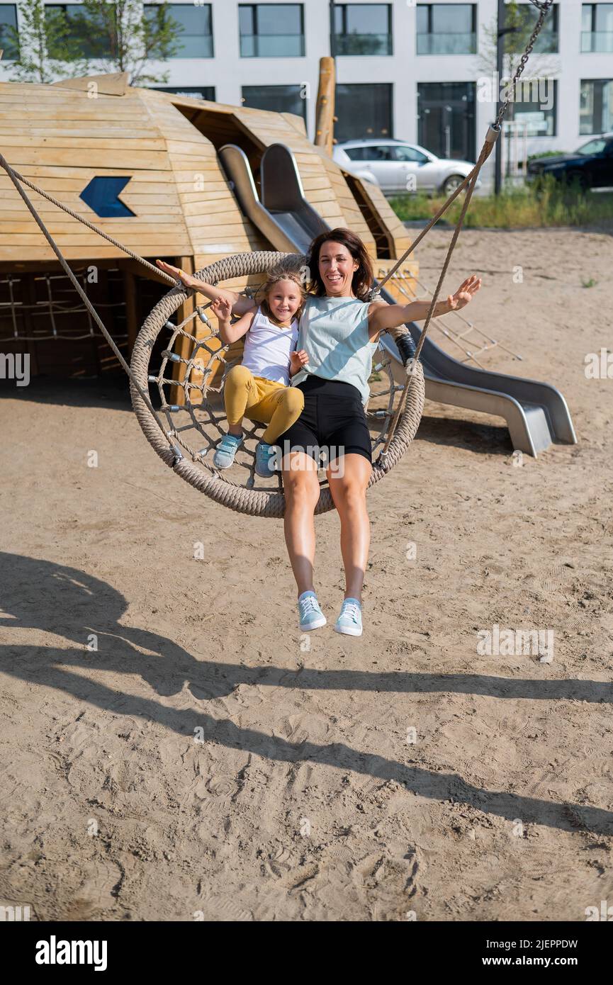 Mom and daughter swing on a round swing. Caucasian woman and little ...