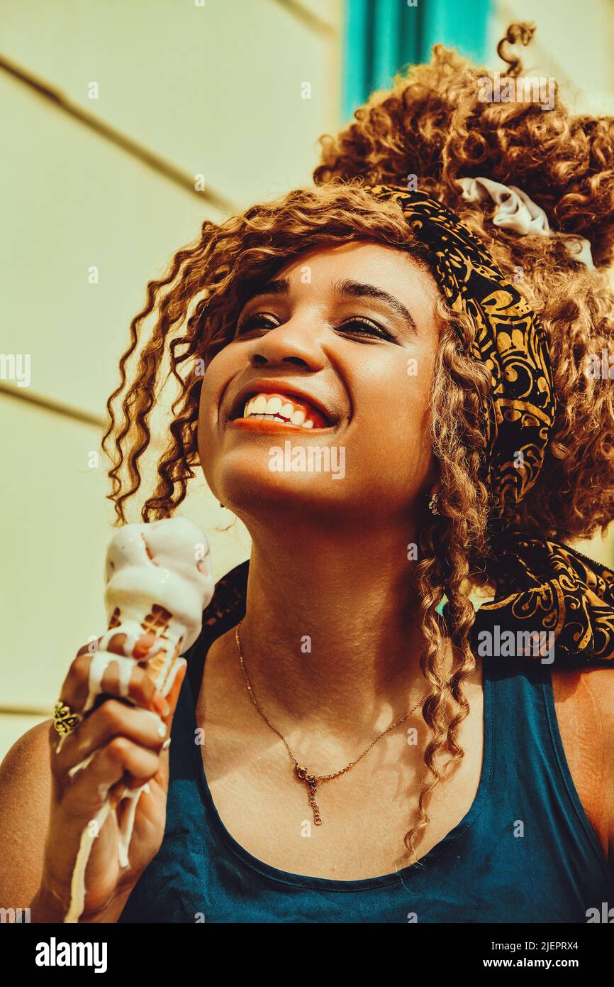 young adult woman afro hair smiling eating ice cream outdoors ...