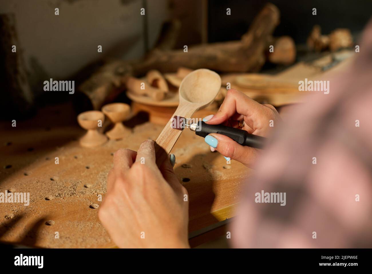 Female using power working tools graver for wooden utensils spoon ...