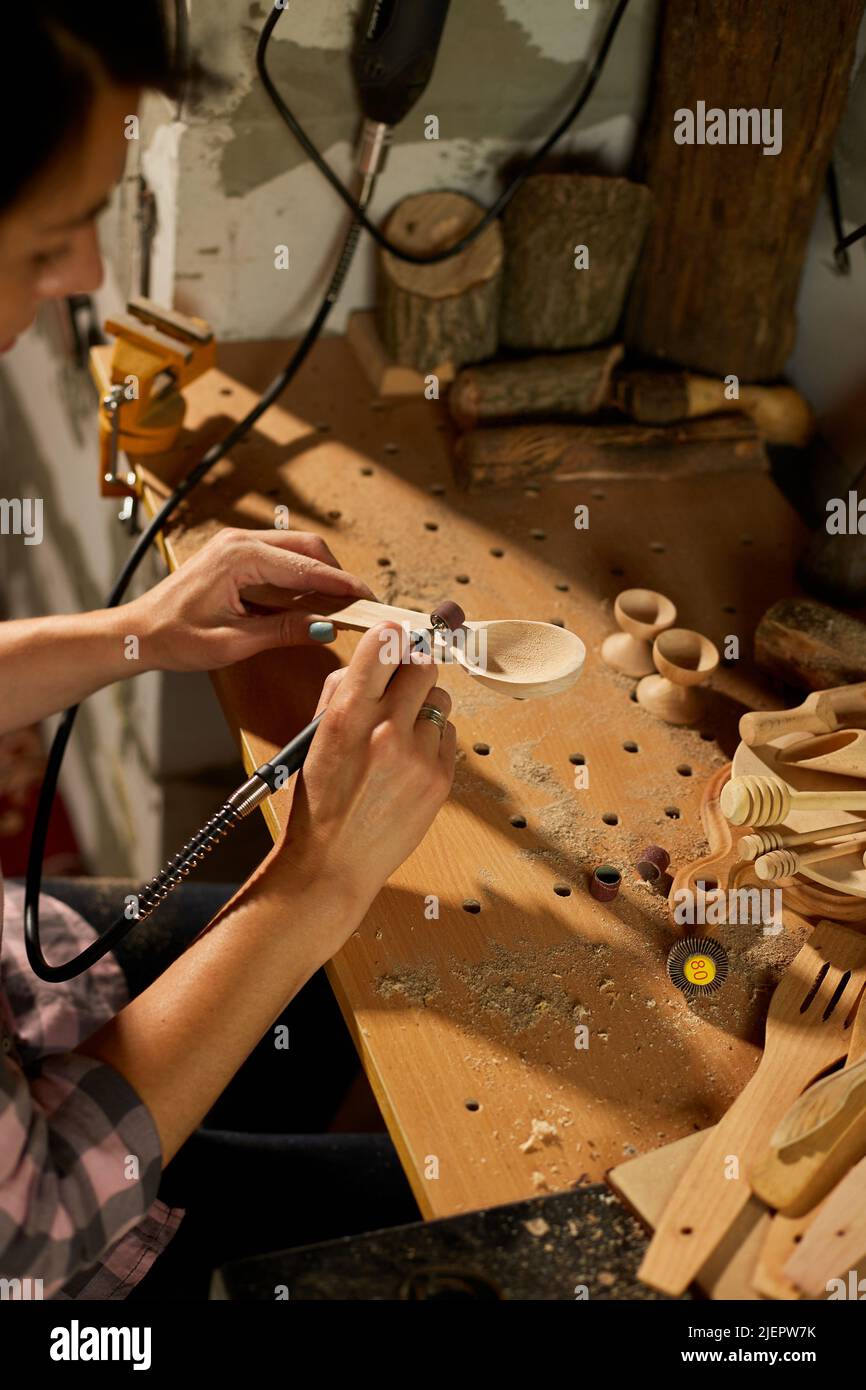 Female using power working tools graver for wooden utensils spoon ...