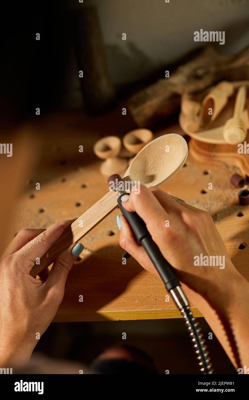Female using power working tools graver for wooden utensils spoon ...