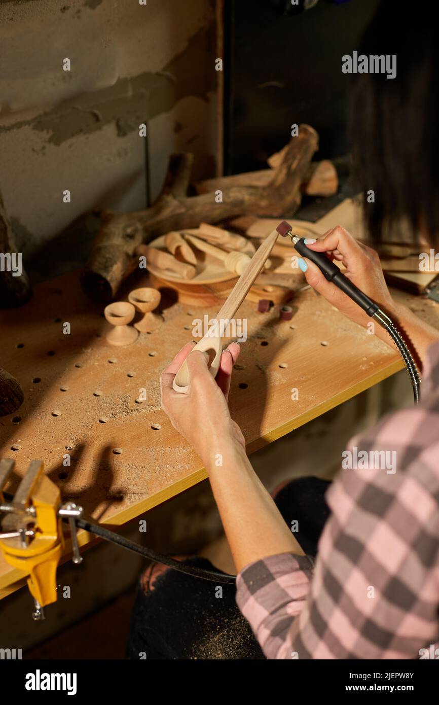 Female using power working tools graver for wooden utensils spoon ...