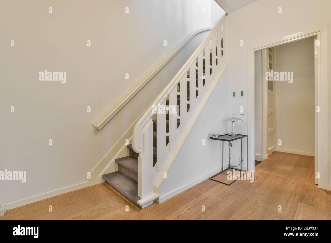 White hallway with wooden stairway leading to second floor of modern ...
