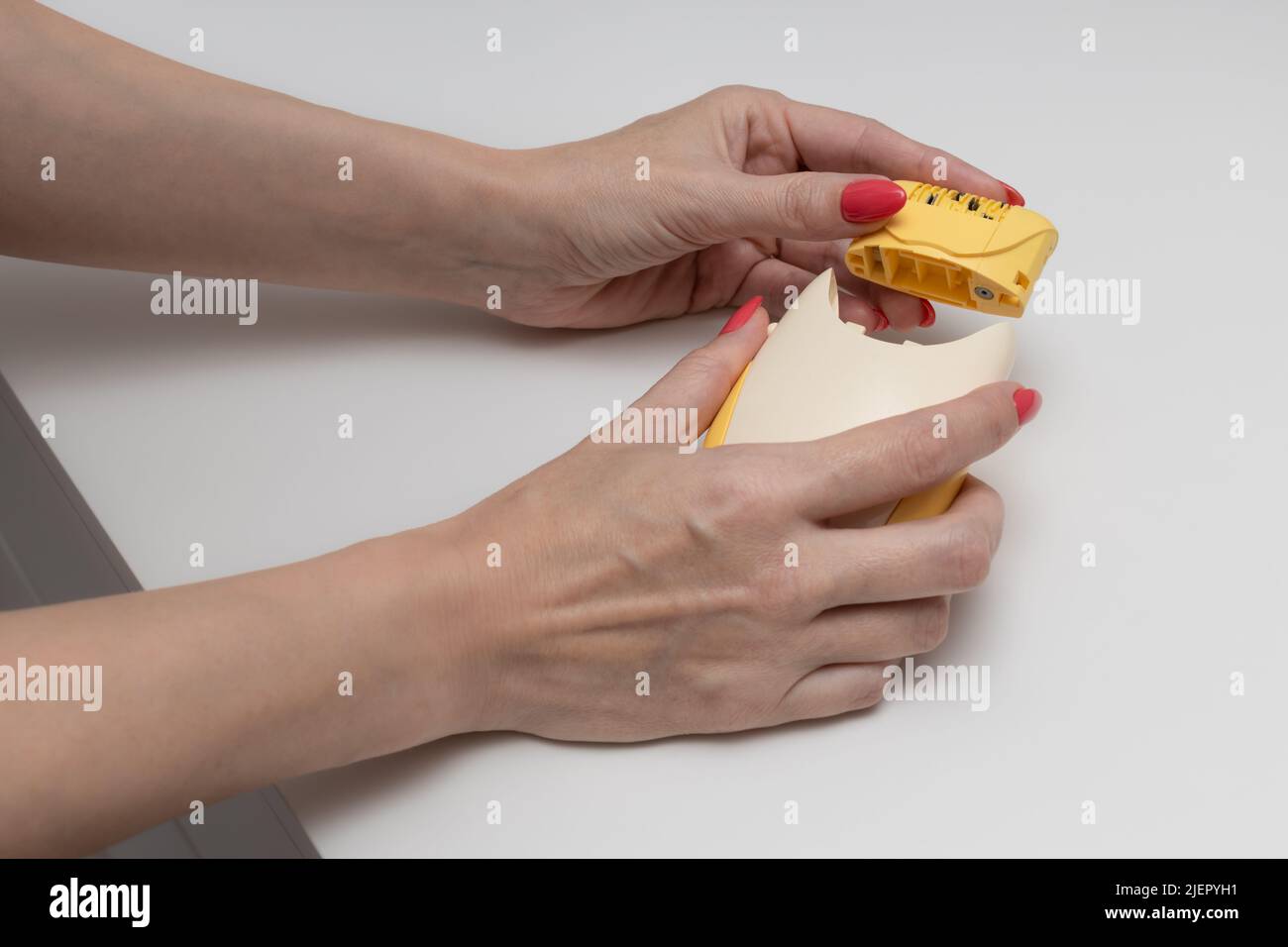woman taking apart her epilator on a white background. High quality ...