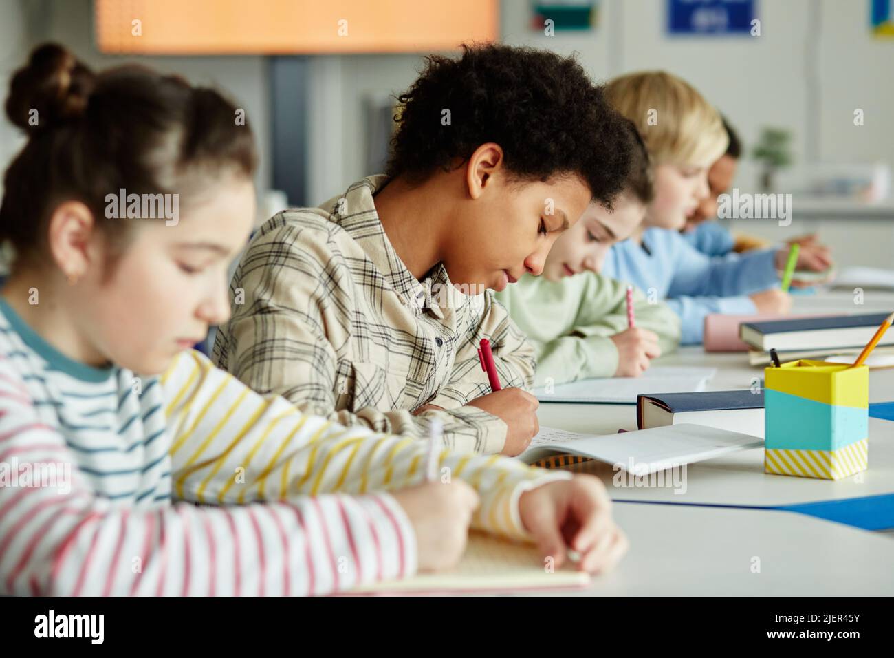 Side view portrait of young black girl taking test in school classroom ...