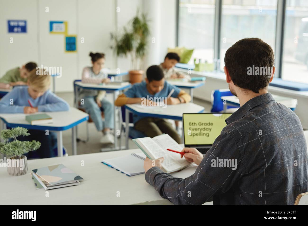 Rear view of teacher with group of kids in school classroom, copy space ...