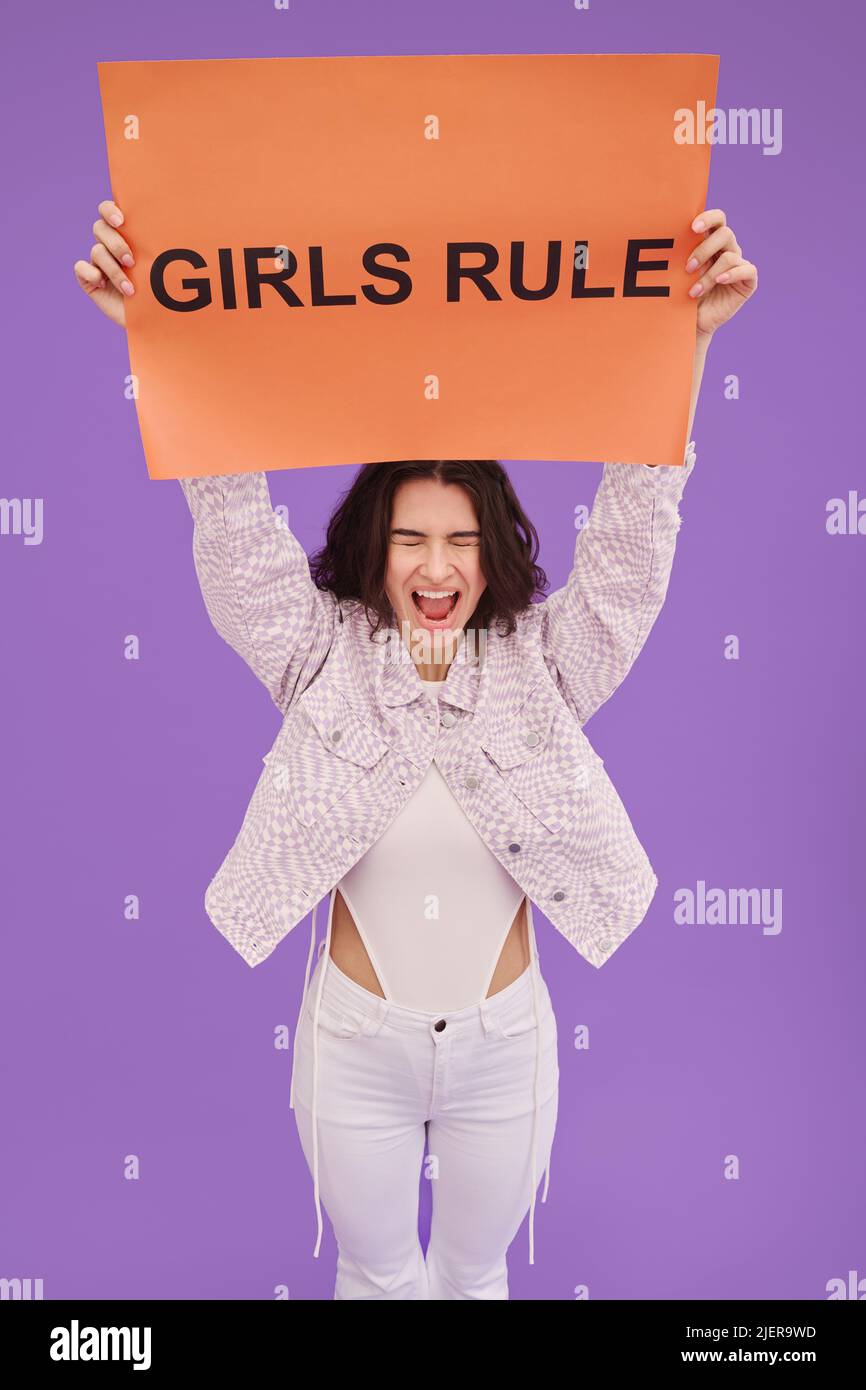 Portrait of young girl holding Girls rule poster above her head and ...