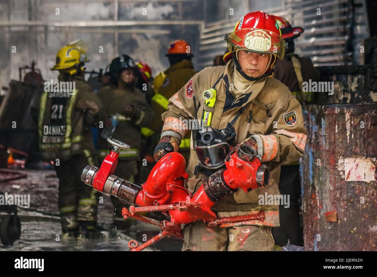 Firefighter exits the fire scene while carrying a pipe in Dela Paz. A ...