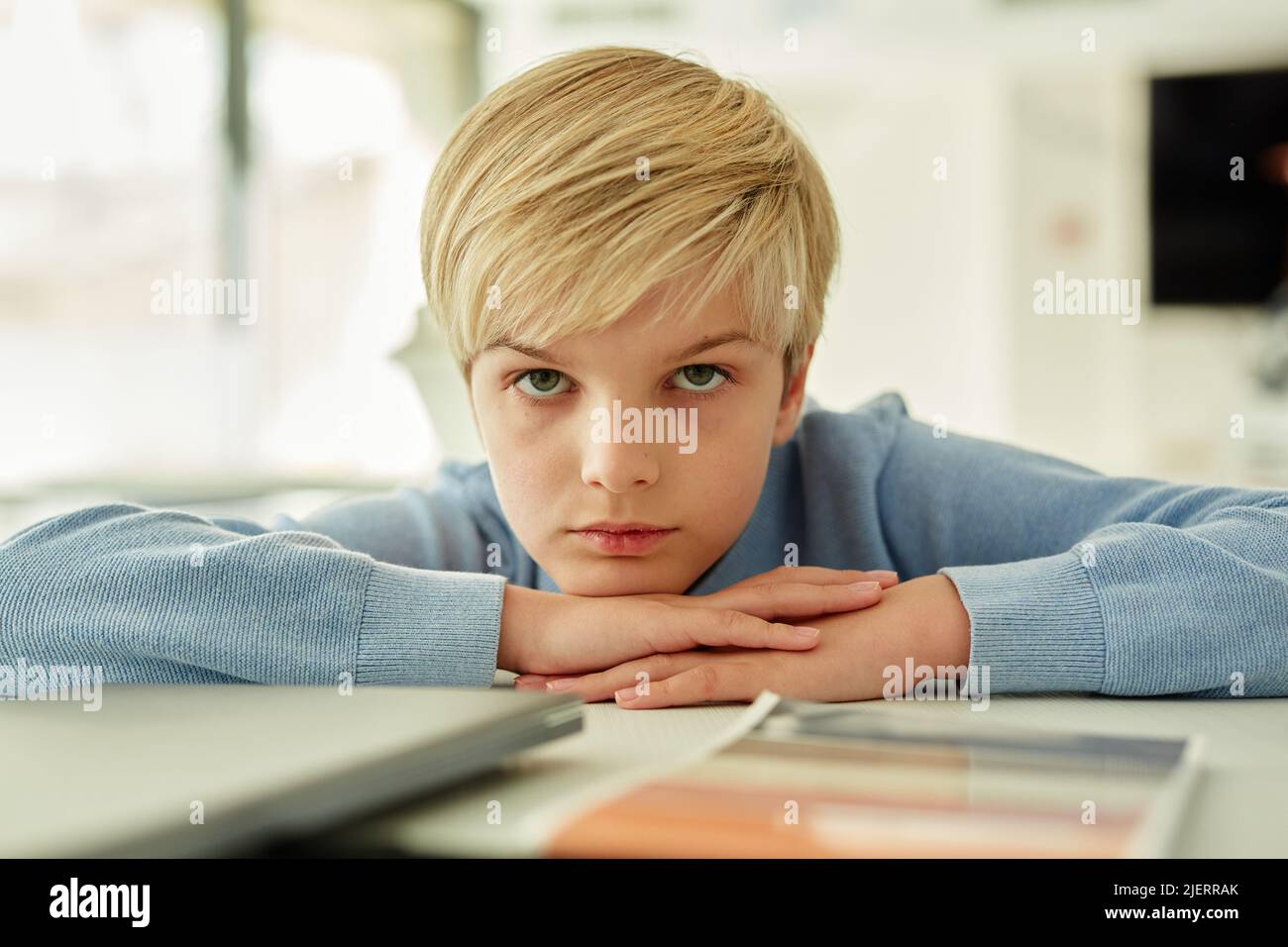 Minimal portrait of bored schoolboy lying on desk in school classroom ...