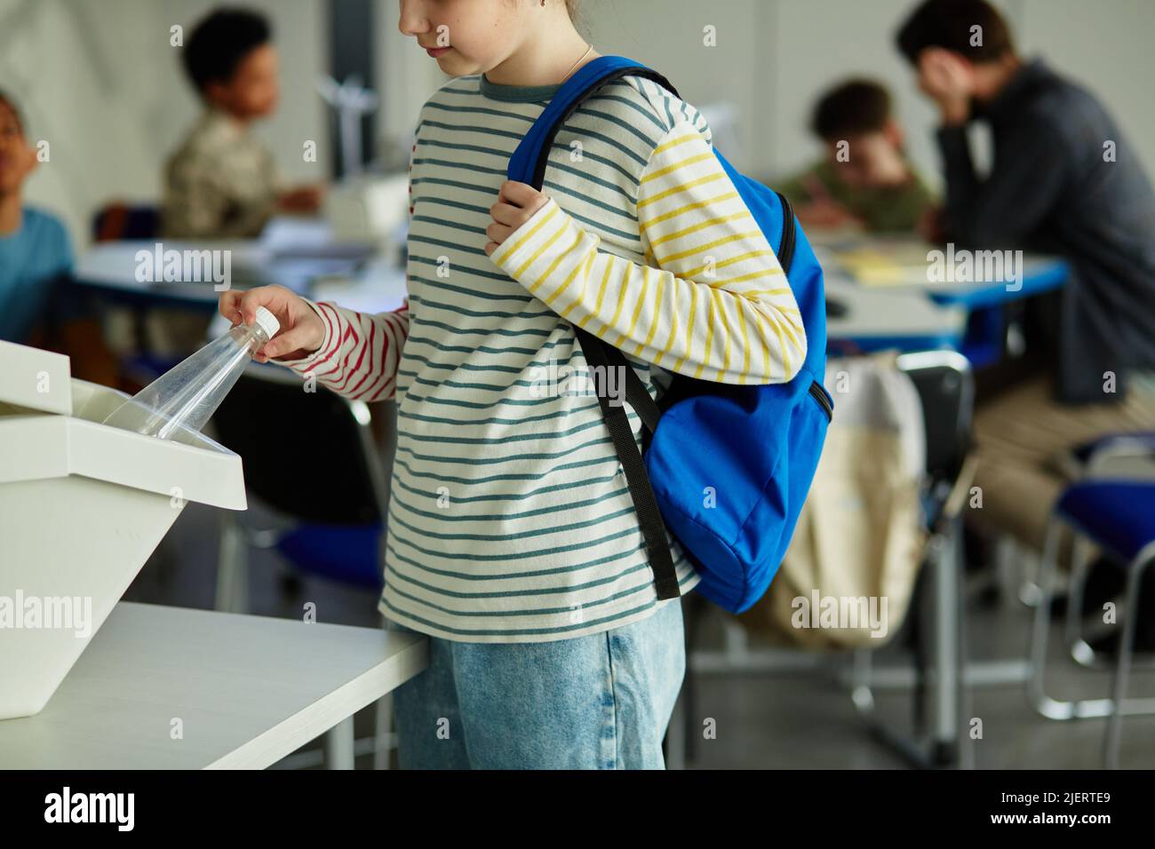 Side view of child using waste sorting bins in school and putting ...