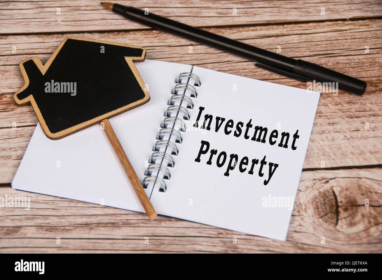 Investment property text on notepad with model house and pen background ...