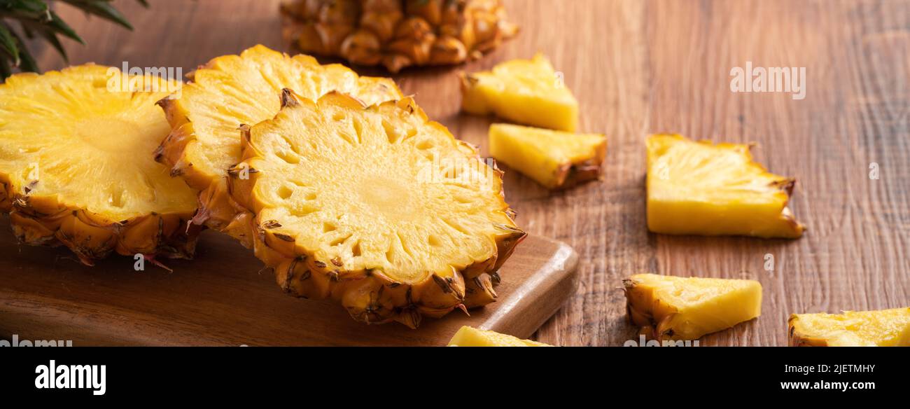 Close up of fresh cut pineapple on a tray over dark wooden table ...