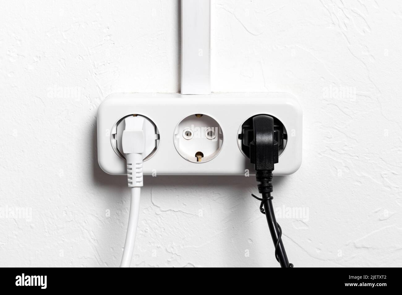 Group of white european electrical outlets with two plugs inserted into ...