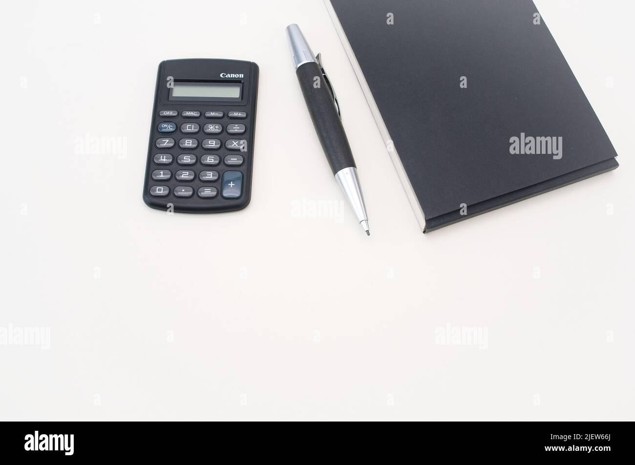 pocket calculator with paper notepad and pencil on a bright white desk ...