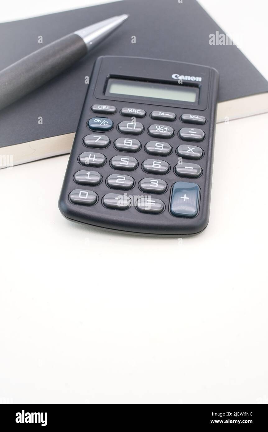 pocket calculator with paper notepad and pencil on a bright white desk ...