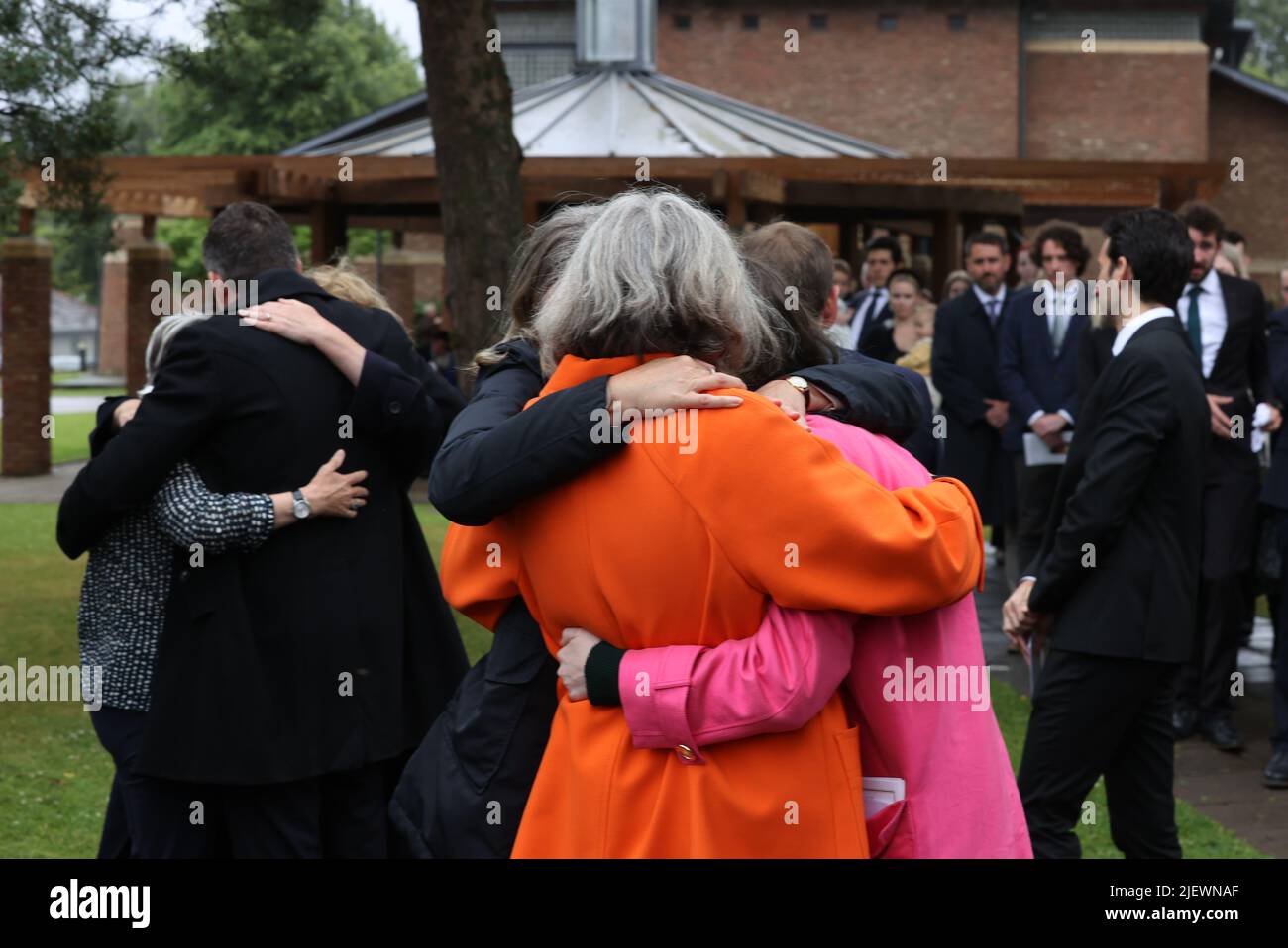 Mourners hug after leaving the funeral of long-time owner of the Irish ...