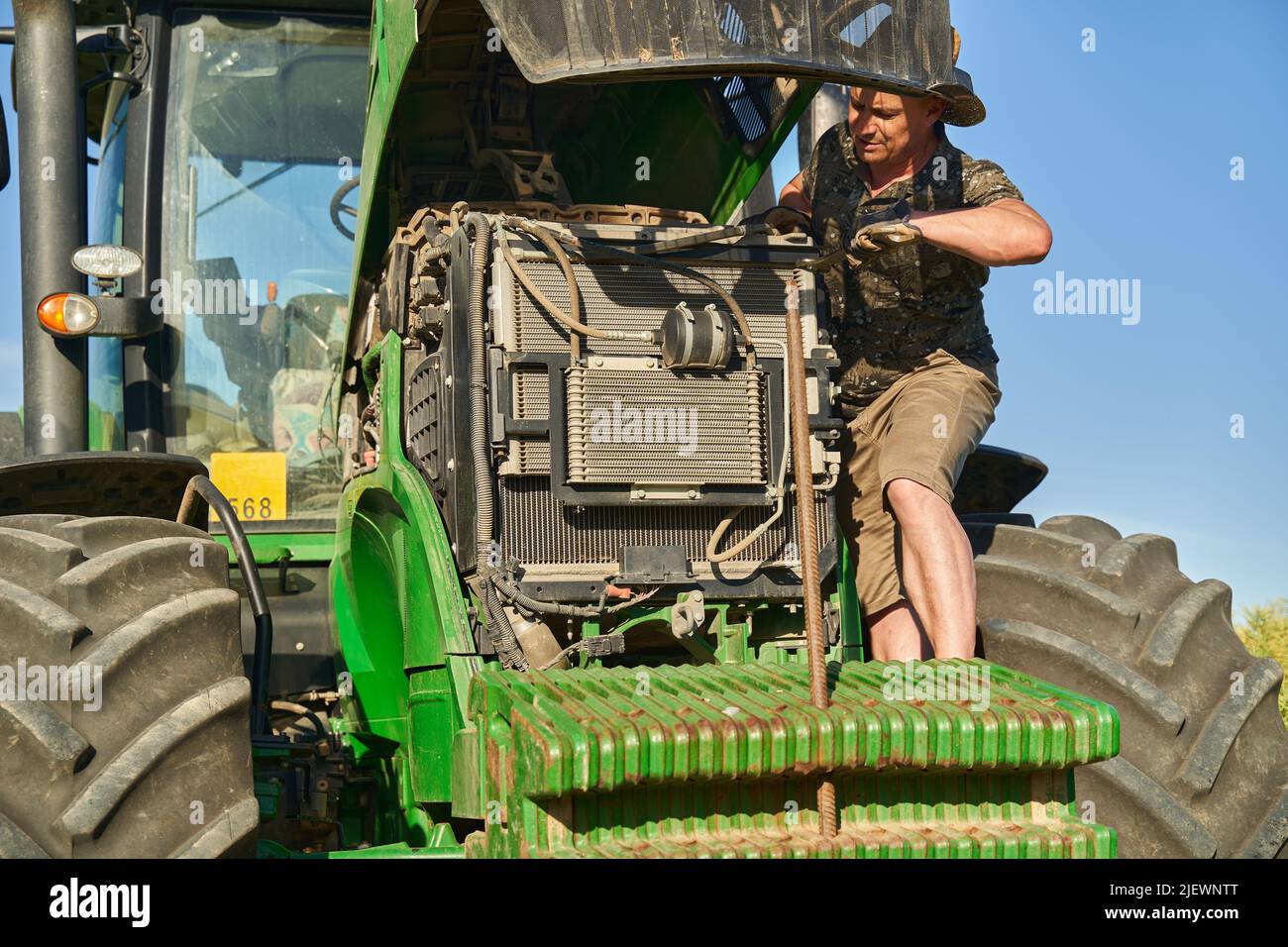 Farmer mechanic trying to repair his broken tractor in the middle of ...
