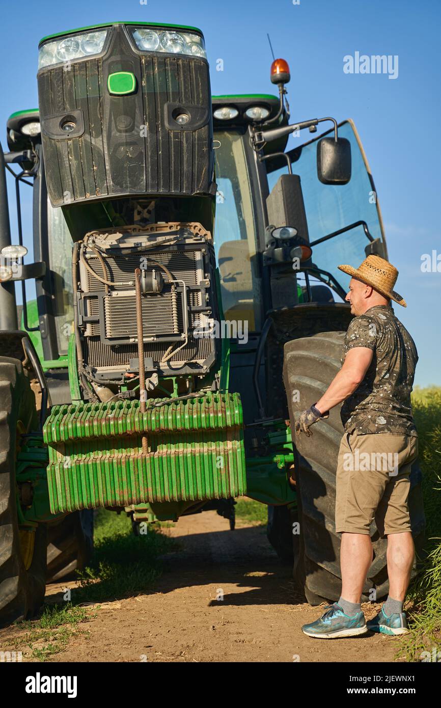 Farmer mechanic trying to repair his broken tractor in the middle of ...