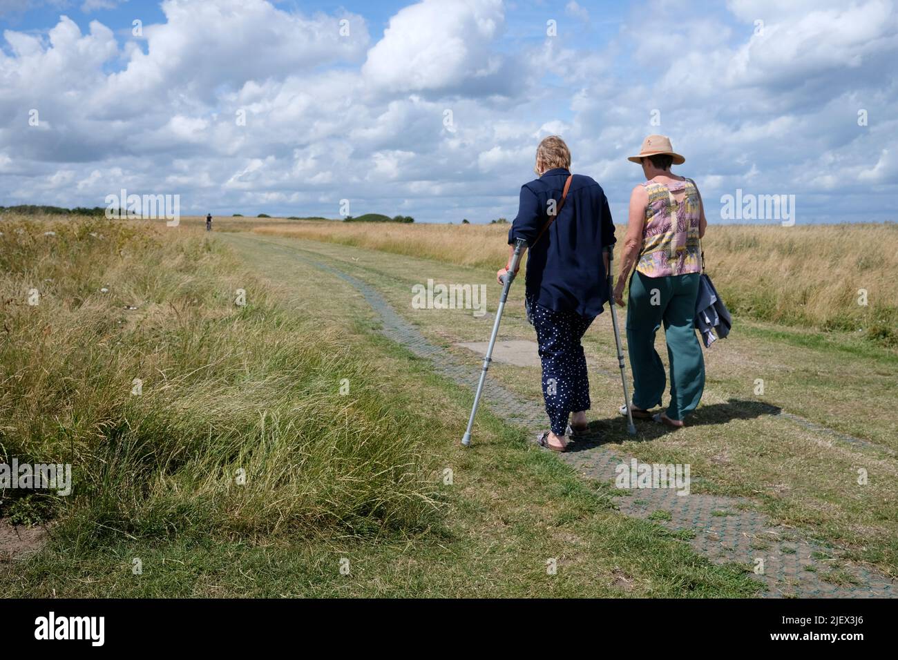 two people walking along the coastal path bishopstone to reculver bay ...