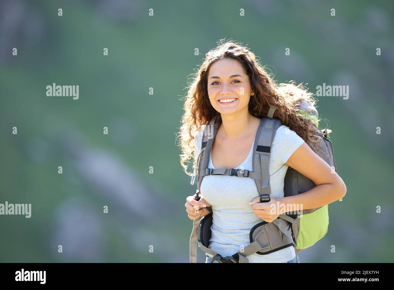 Happy hiker wearing backpack posing looking at you in the mountain ...