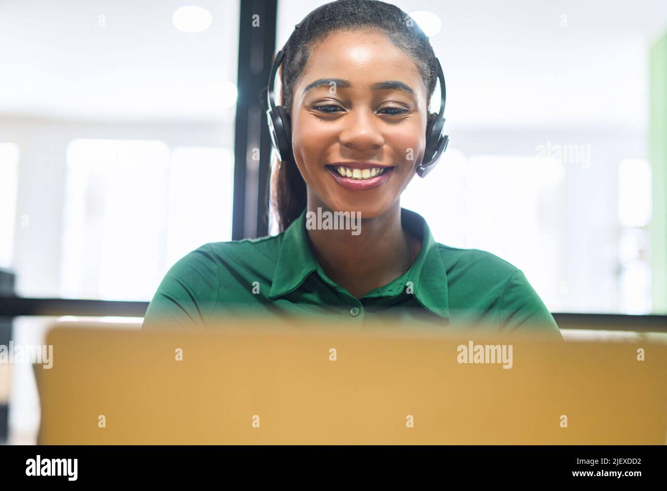 Smiling african-american female employee colleague using headset and ...