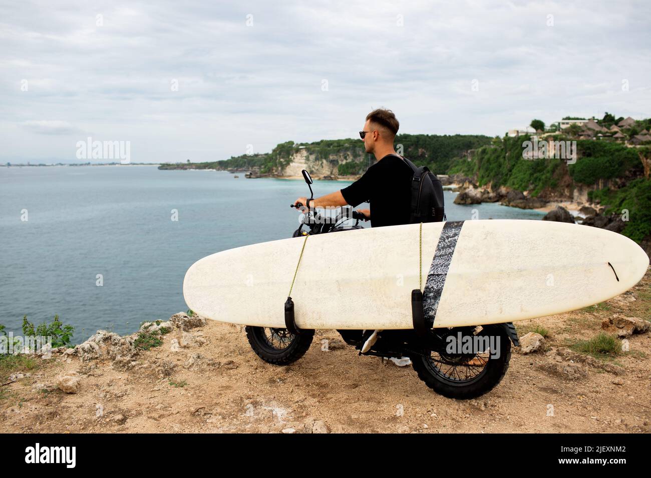 young man sits on a motorcycle with a surfboard. high quality photo ...