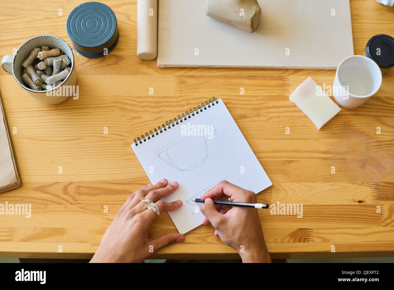 Above angle of hands of young craftsman or artisan drawing sketch of ...
