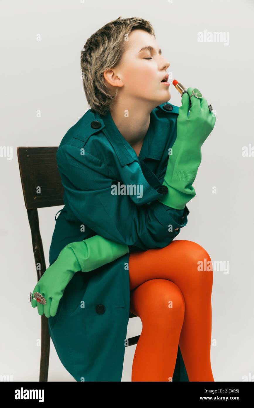 Portrait of stylish young girl in extravagant outfit, applying red ...