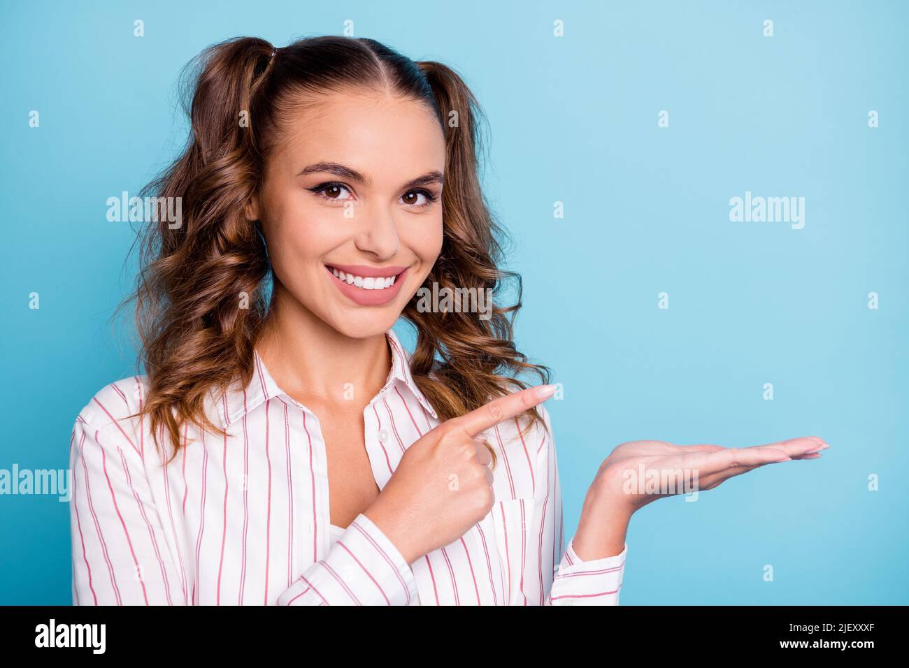 Portrait of lovely cheerful brown-haired girl holding on palm demonstrating copy space ad ...