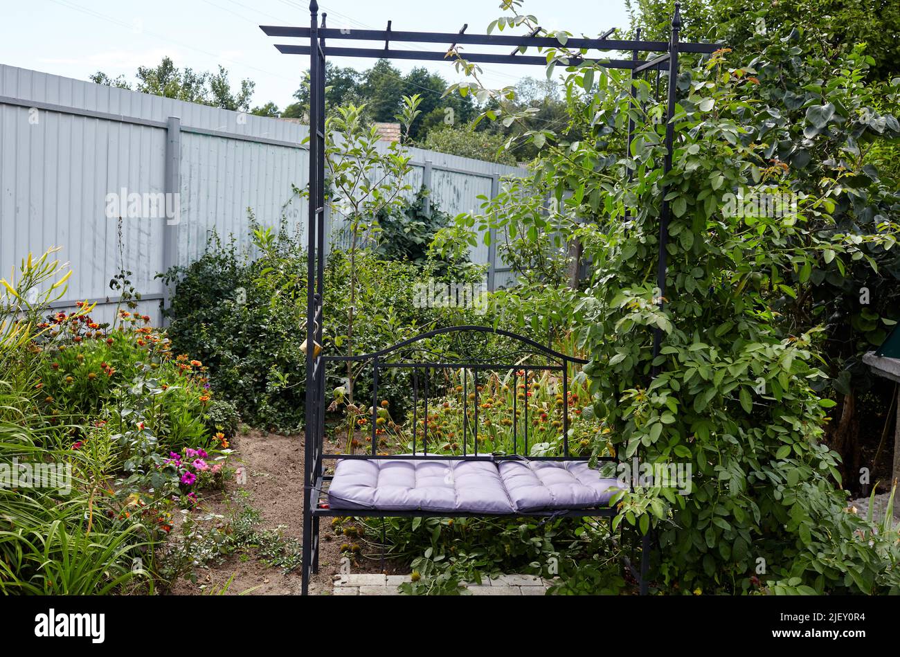 Garden rest area with metal bench surrounded by blooming flowers and ...